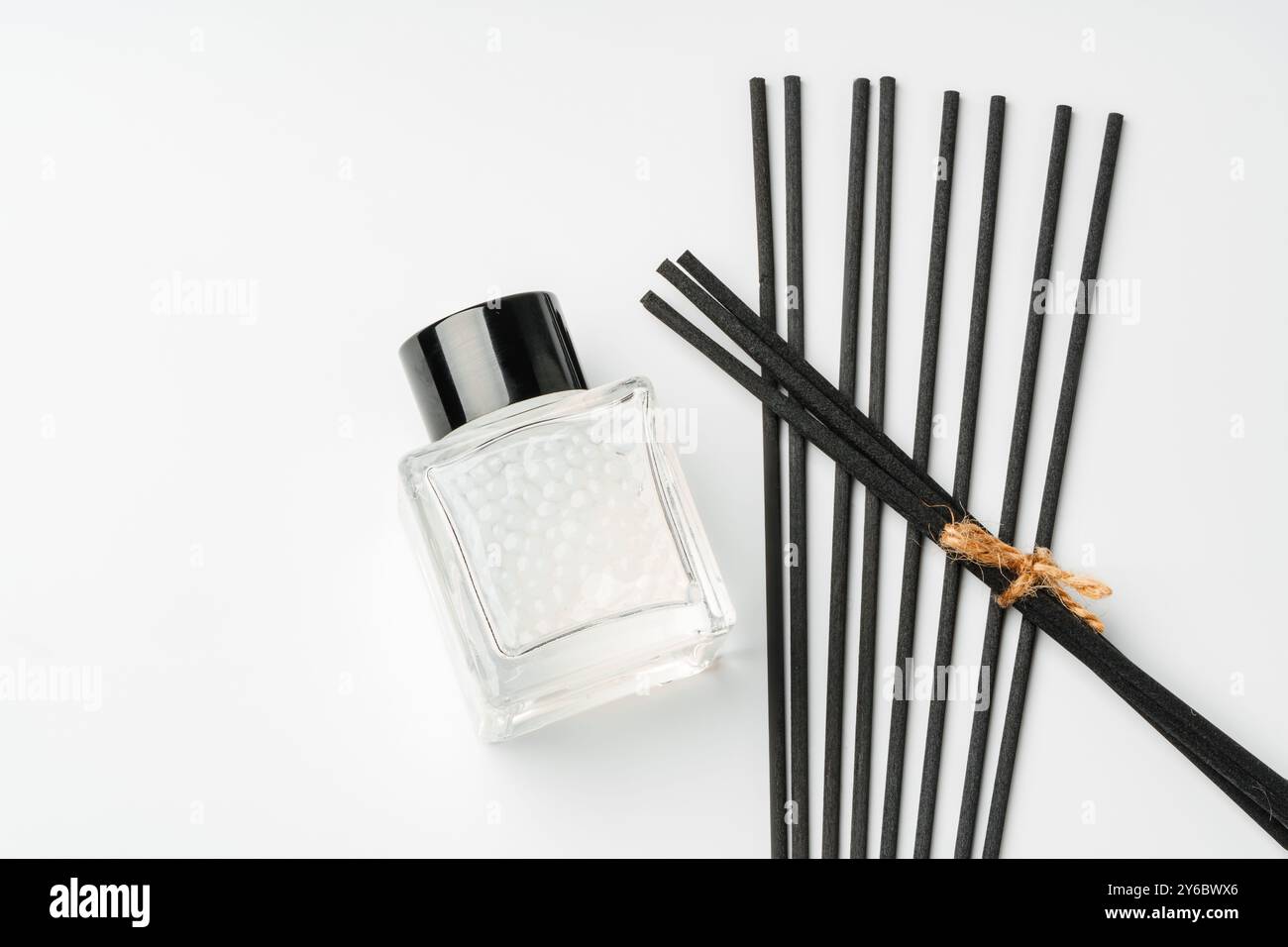 A minimalist display of essential oil and black diffuser sticks on a ...
