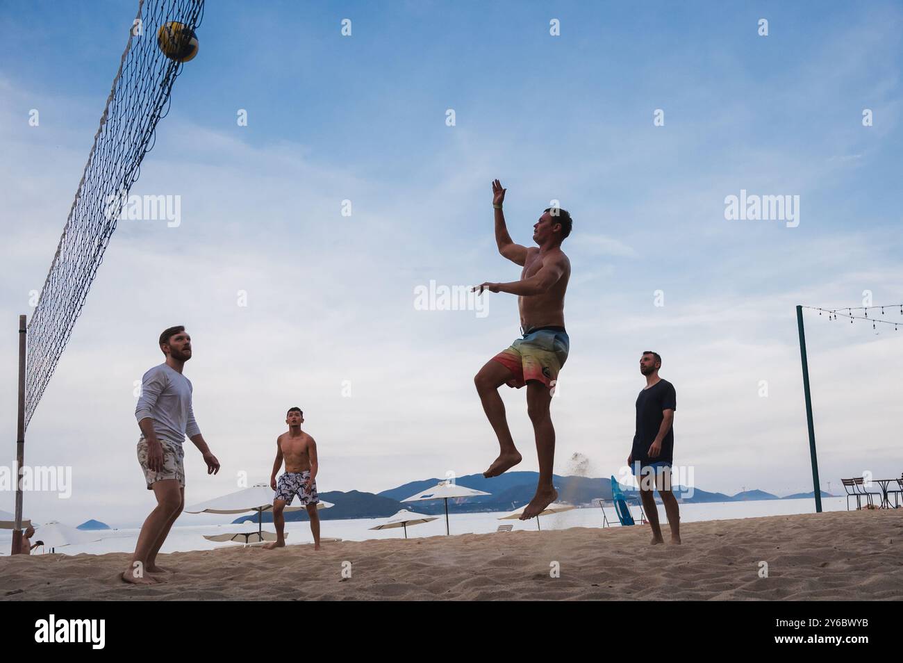 Teams with multinational players play beach volleyball by the sea in ...