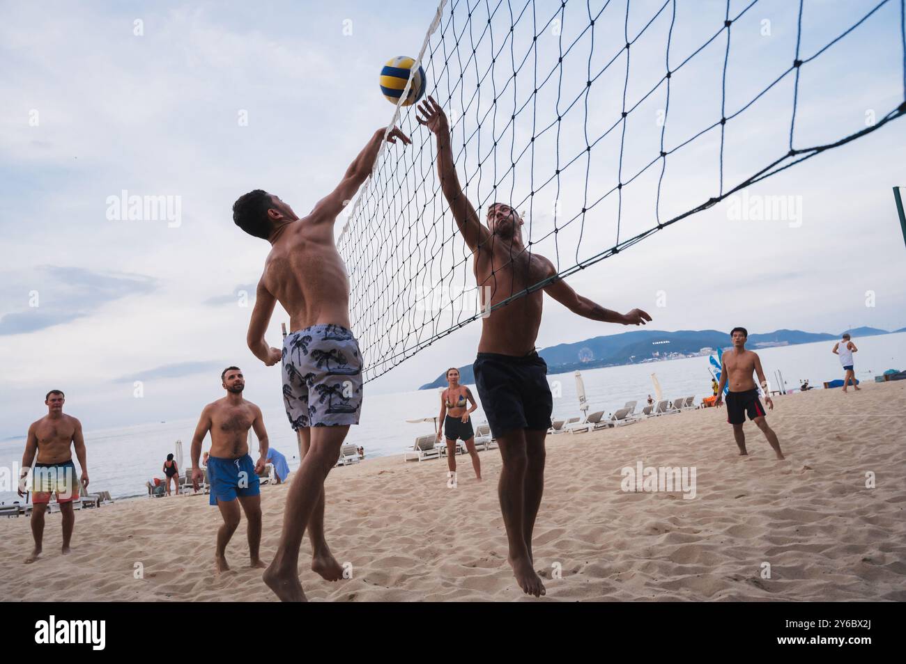 Teams with multinational players play beach volleyball by the sea in ...