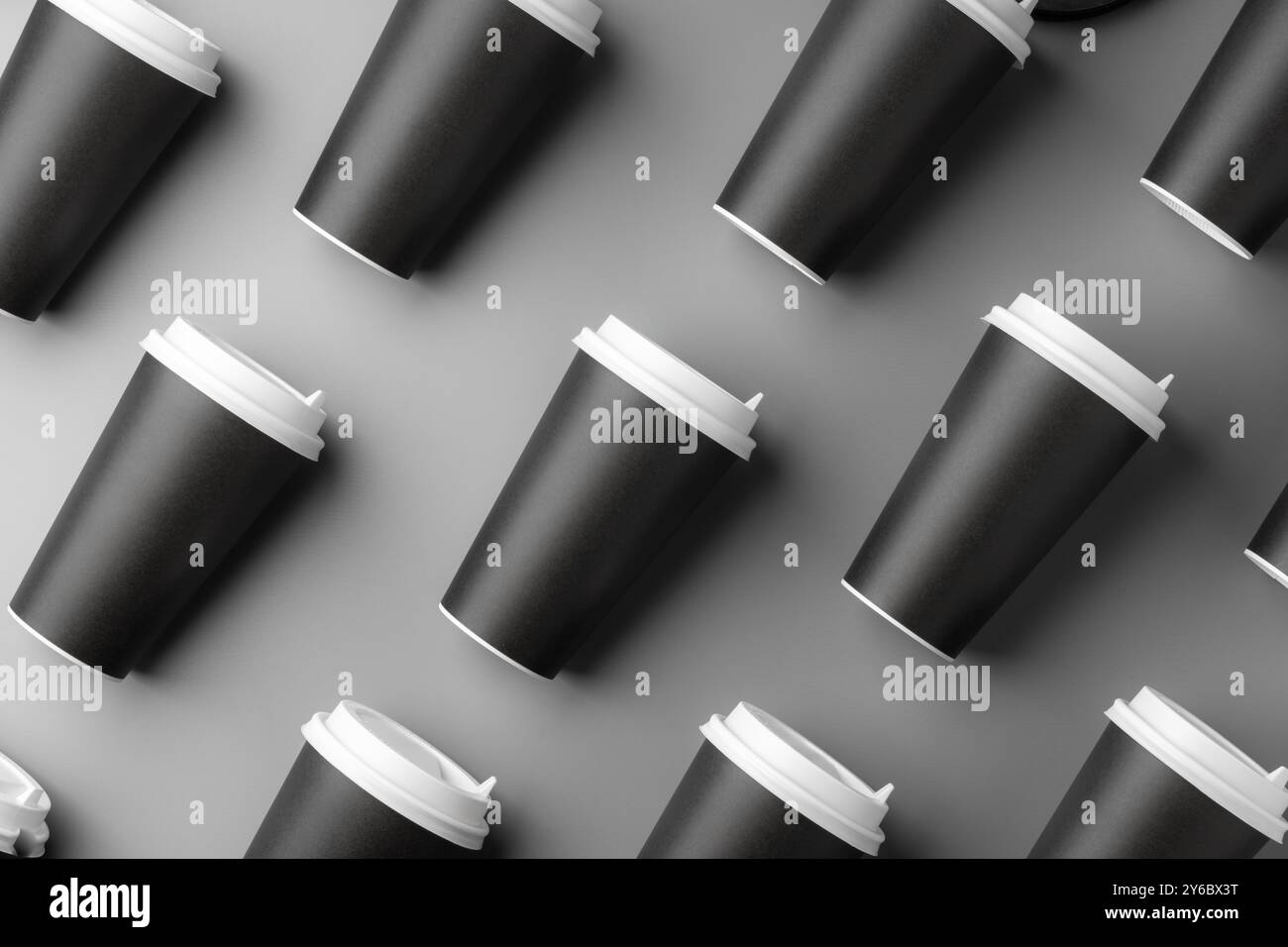 Black disposable cups arranged on a gray surface with white lids ...