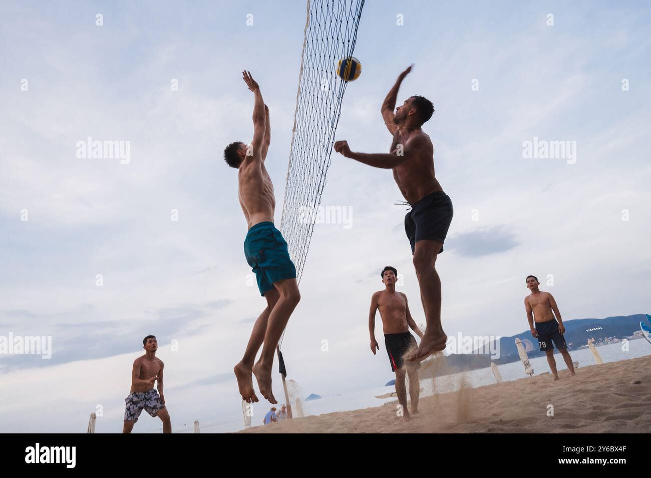 Teams with multinational players play beach volleyball by the sea in ...