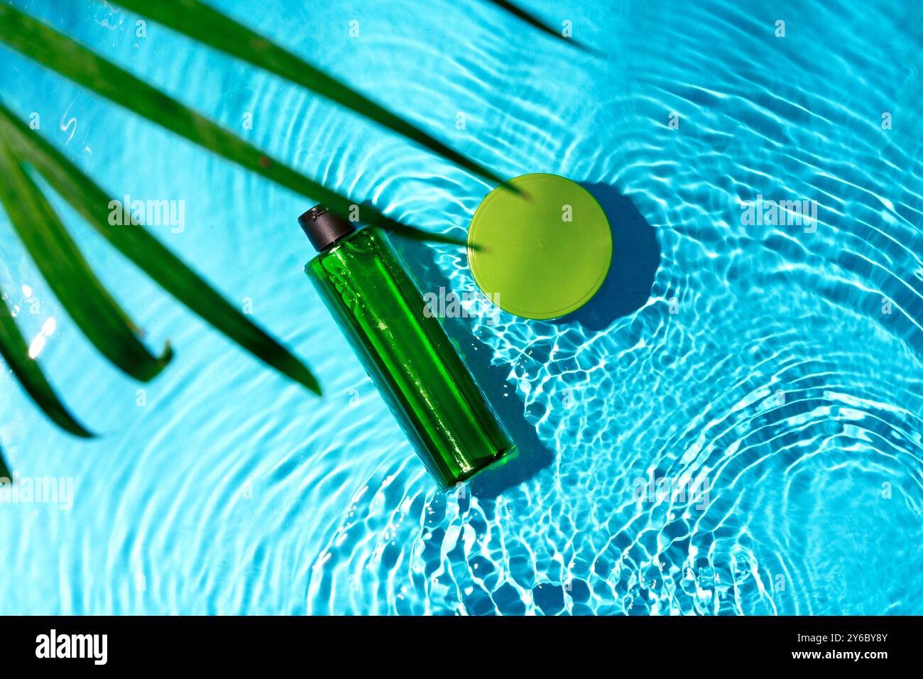 Green bottle floating on a clear blue swimming pool during bright ...