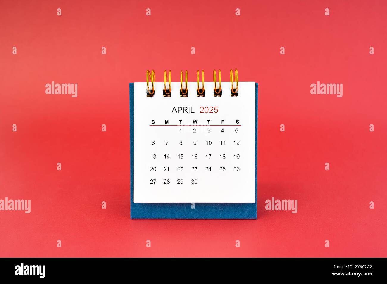 April 2025 white desk calendar on red color background Stock Photo - Alamy
