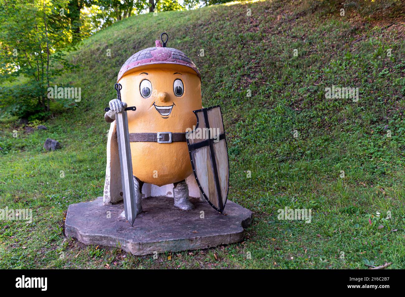 An acorn statue of a friendly character holds a sword and shield in a ...