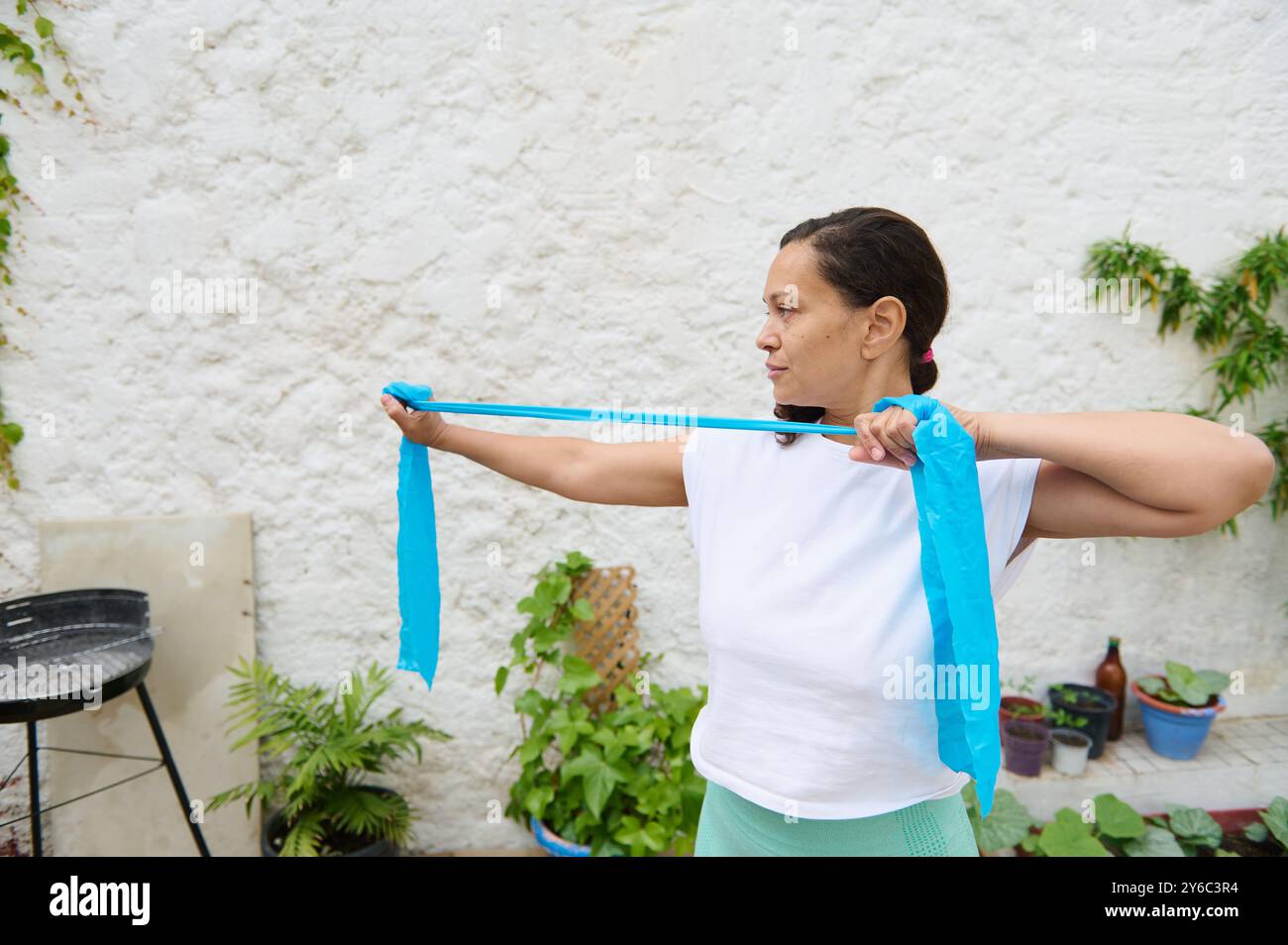 A woman performing a stretching exercise with a blue resistance band in ...