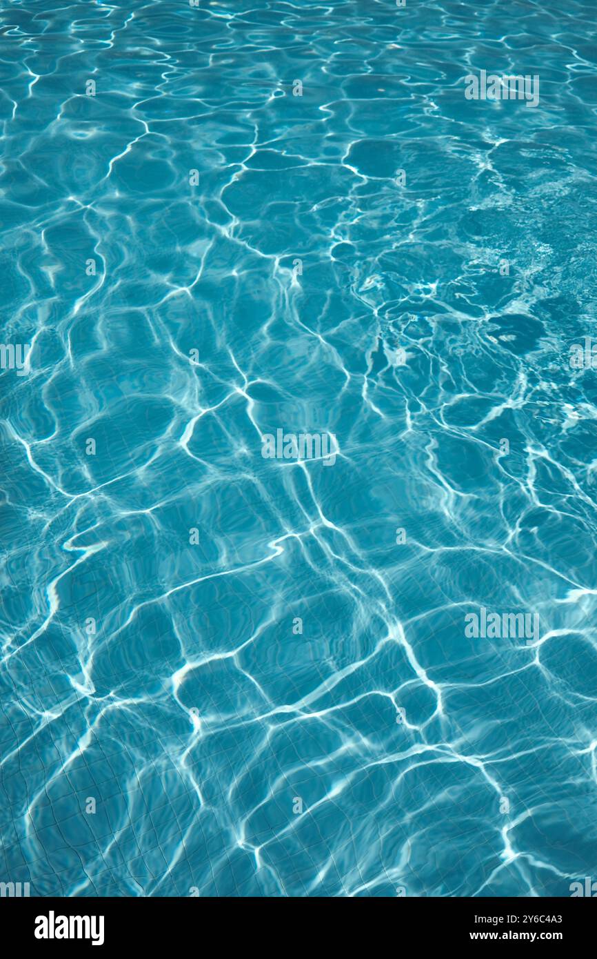 A close-up of clear blue water in a swimming pool with sunlight ...