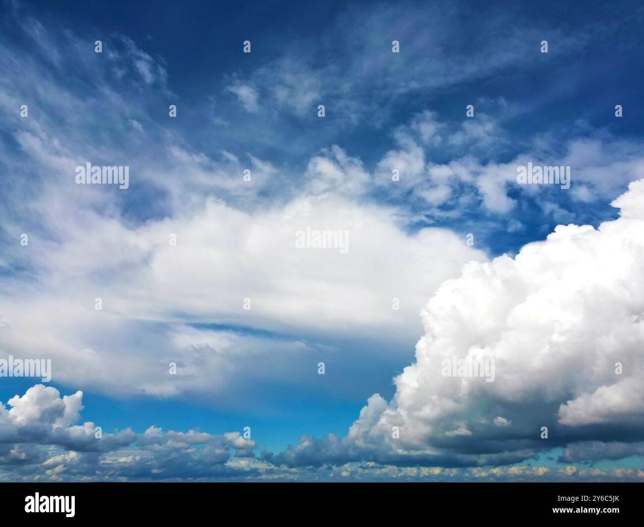 A vibrant blue sky filled with various types of clouds, creating a ...