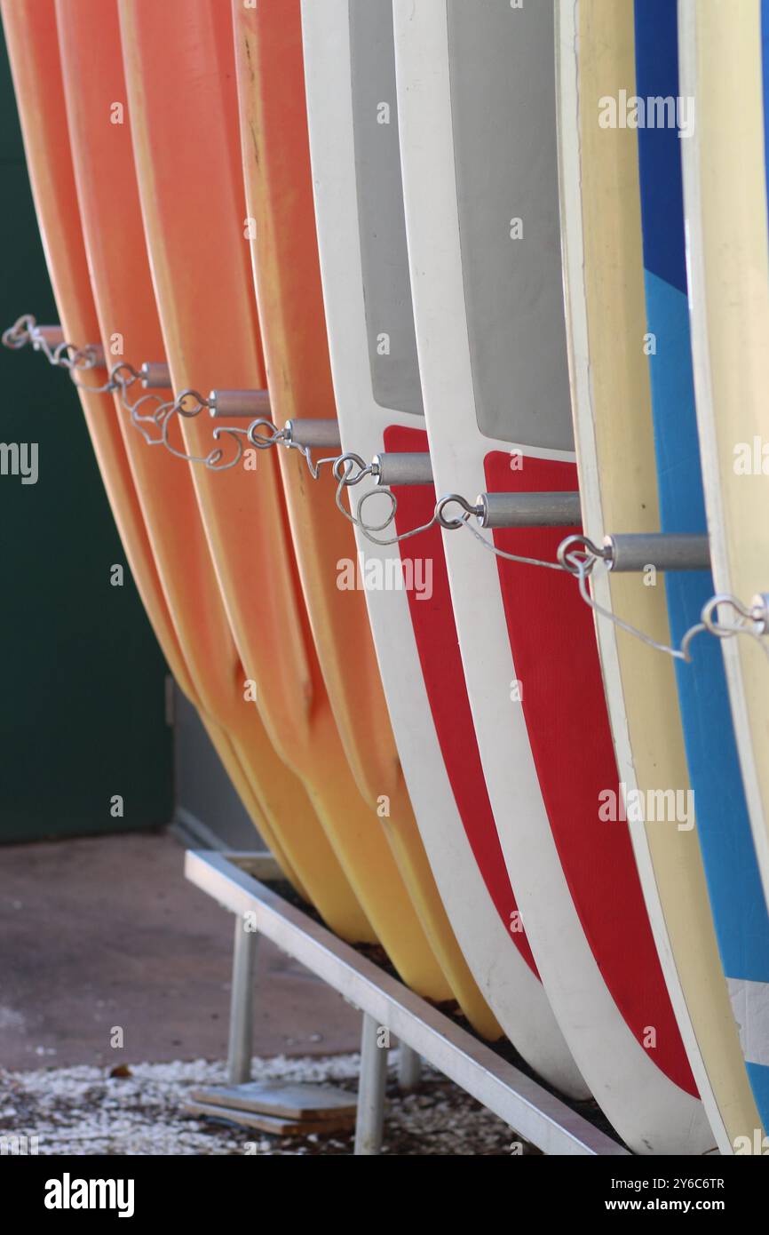 Colorful surfboards lined up in a rack, ready for use at a beachside ...