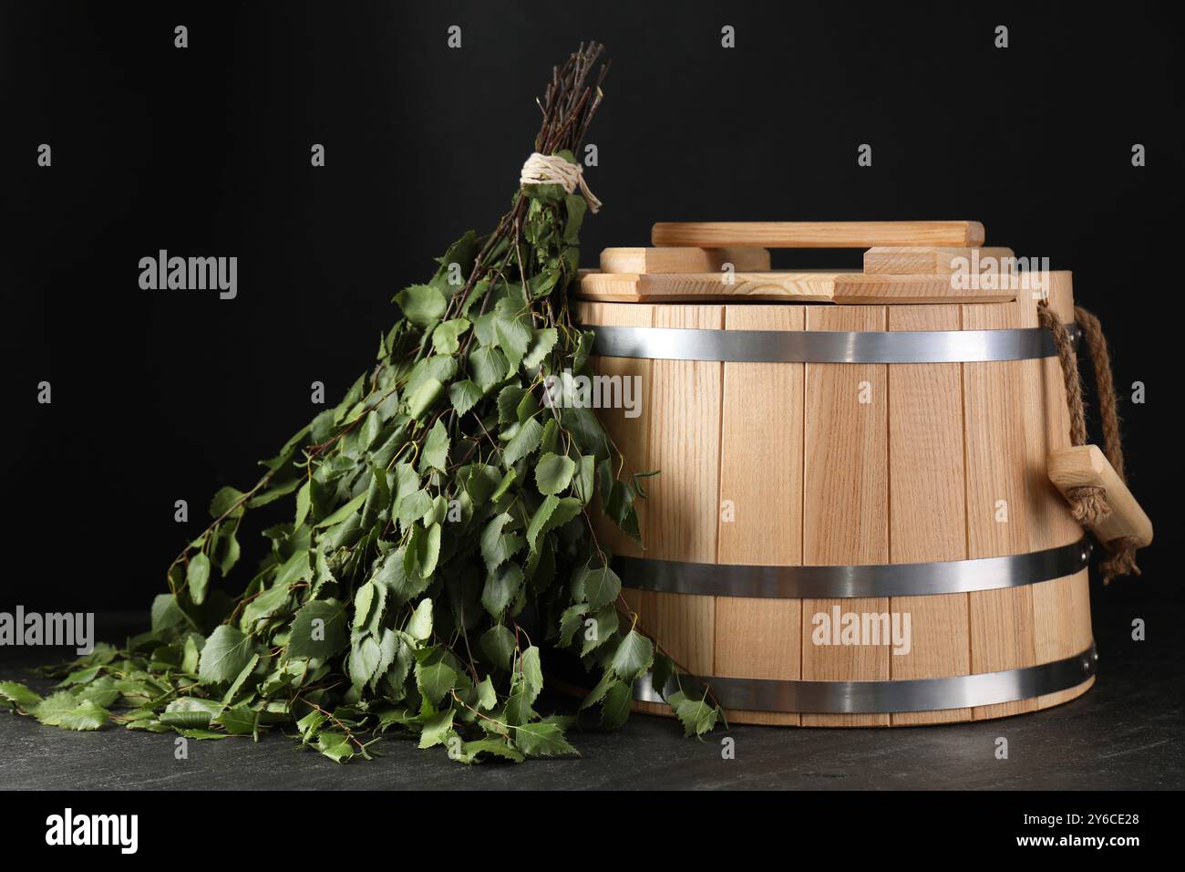 Sauna equipment. Bucket and birch whisk on black textured surface Stock ...