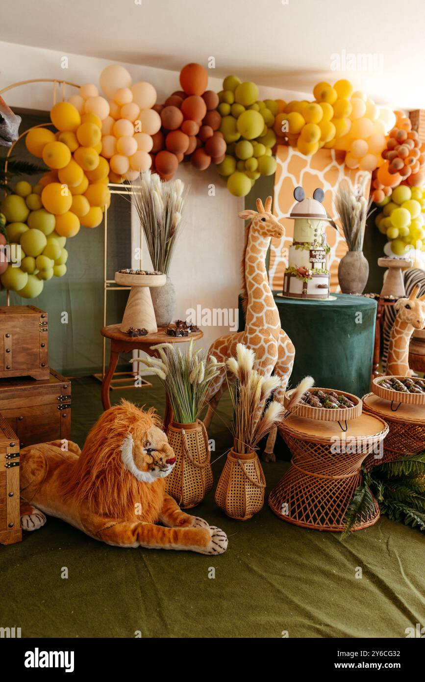 A kids' jungle-themed birthday party setup with stuffed animals, balloons, and decorative ...