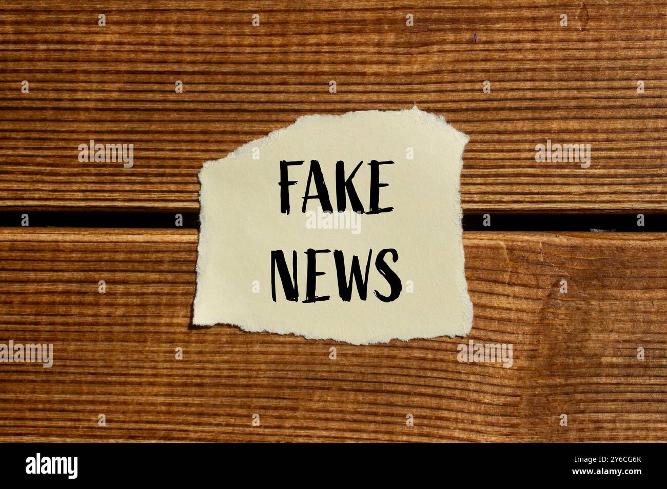 Fake news message written on ripped torn paper with wooden background ...
