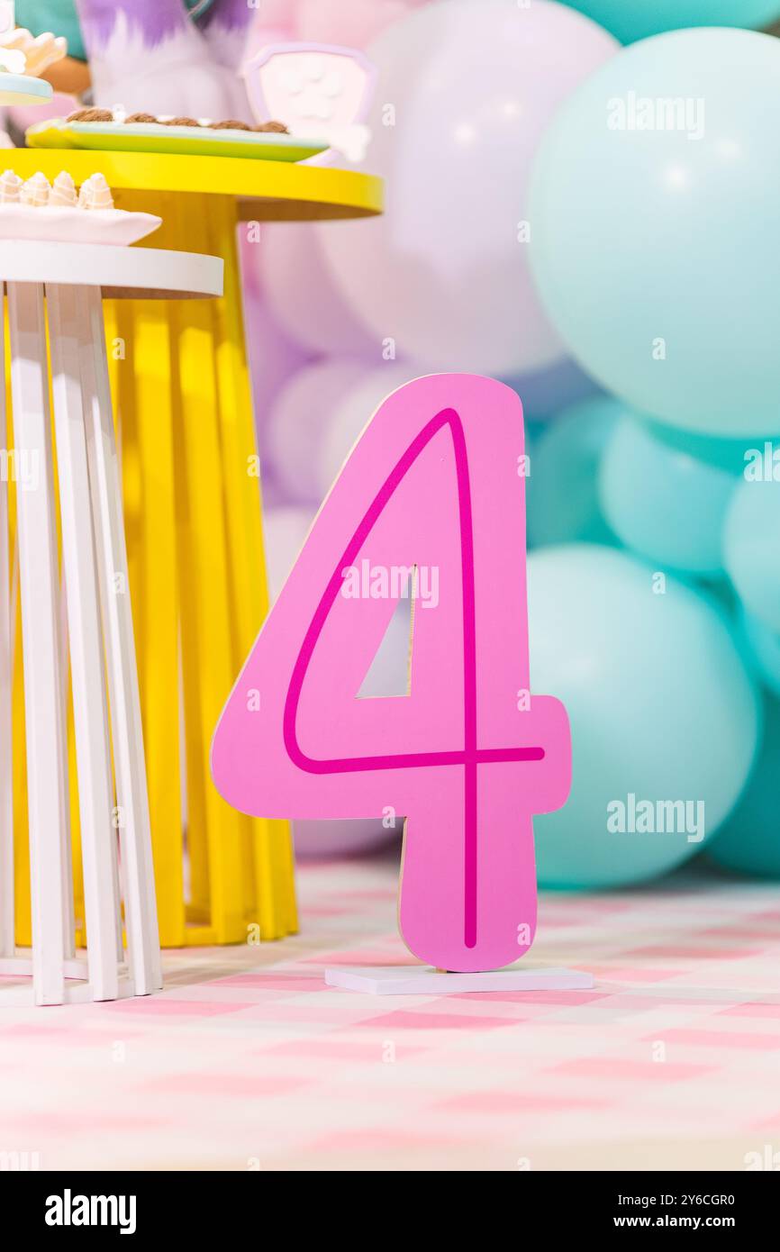 A colorful birthday party setup with a pink number 4 decoration, yellow ...