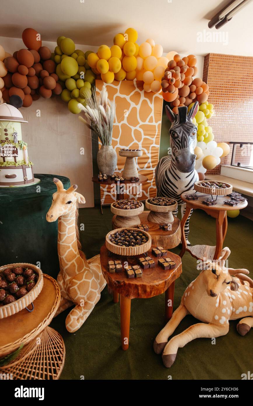 A safari-themed dessert table with plush animal toys, wooden tables ...