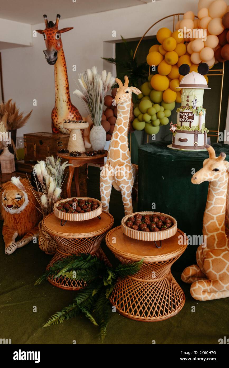 Safari-themed party setup with giraffe and lion plush toys, wicker ...
