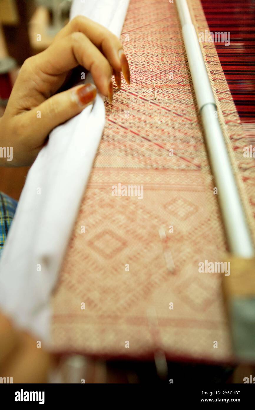 A traditional songket fabric and the fingers of a female worker who ...