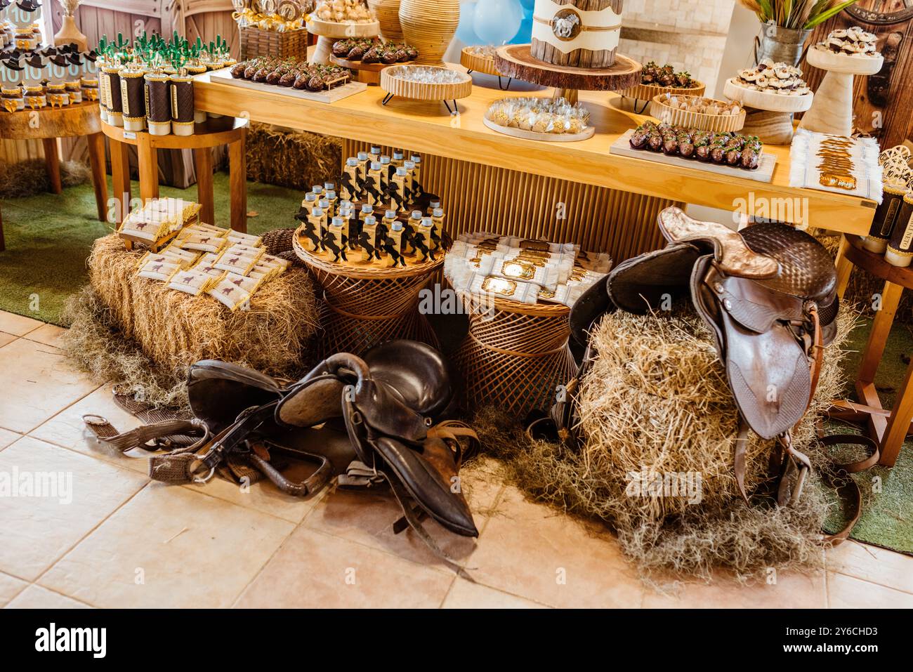 Decorated dessert table with cowboy theme, featuring saddles, hay bales ...