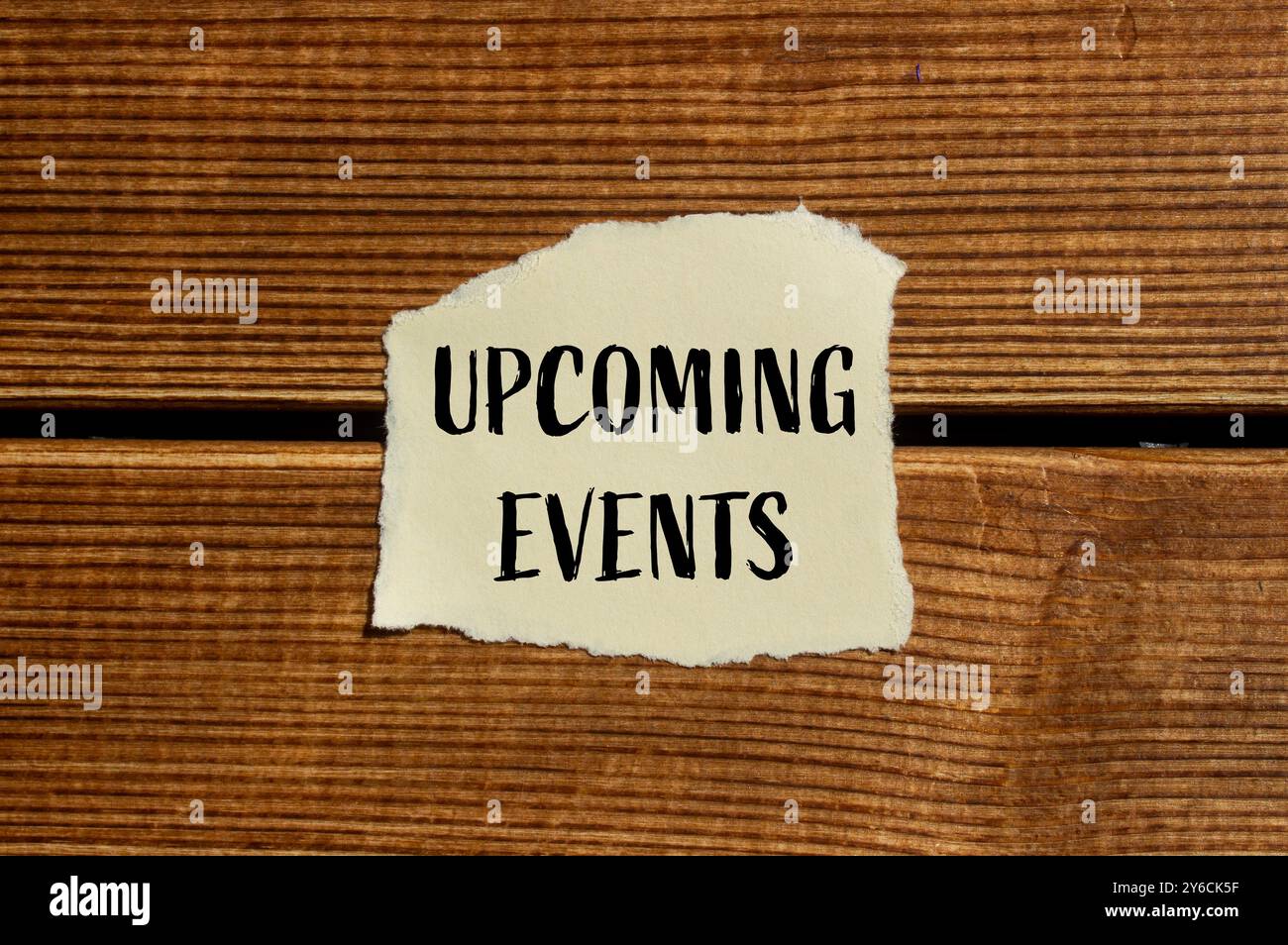 Upcoming events message written on ripped torn paper with wooden ...