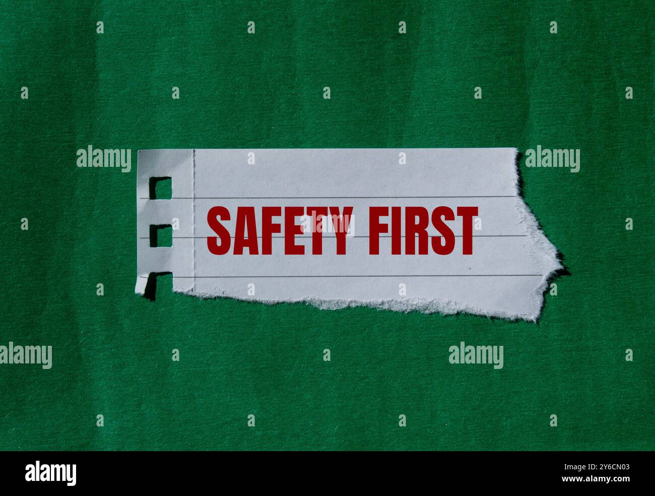 Safety first message written on ripped torn paper with green background ...