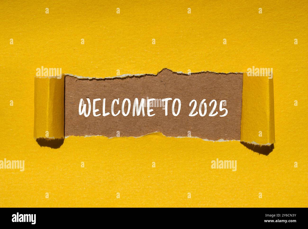 Welcome to 2025 message written on ripped torn yellow paper with brown ...