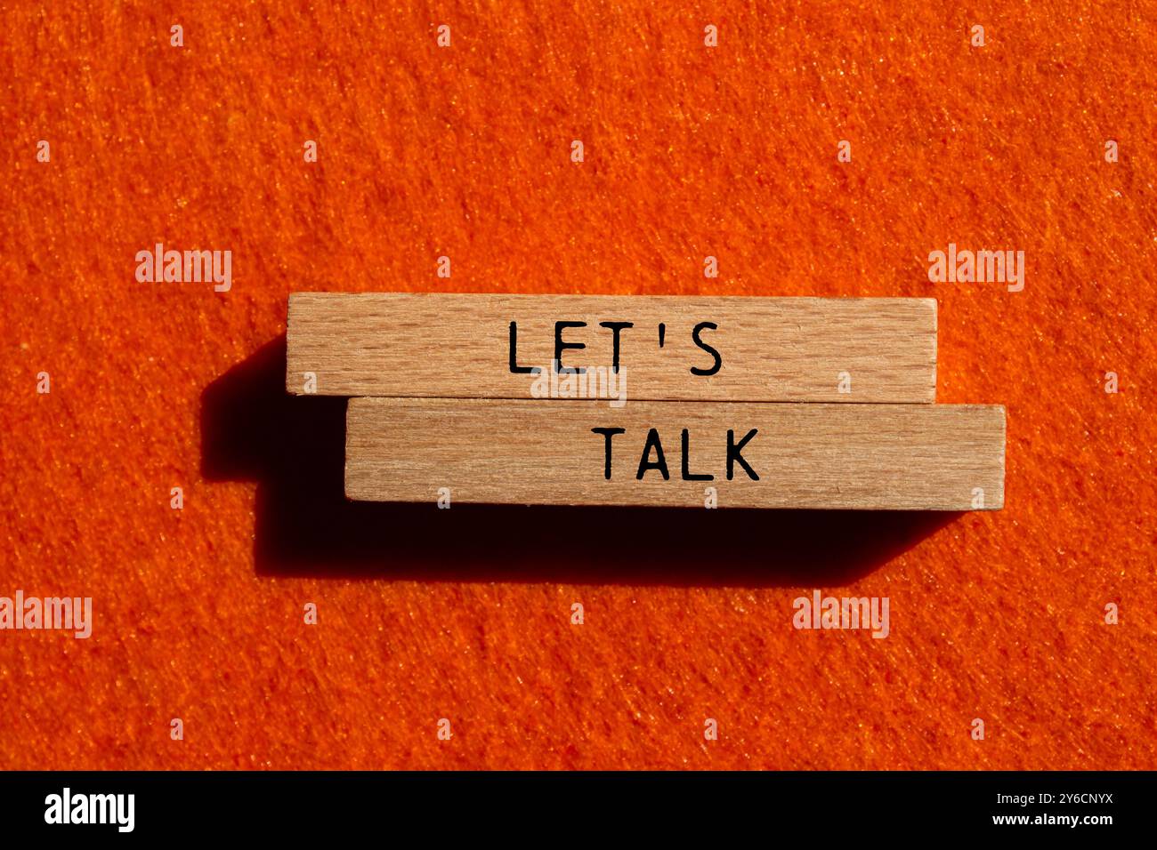 Let's talk message written on wooden blocks on orange felt background. Conceptual let's talk ...