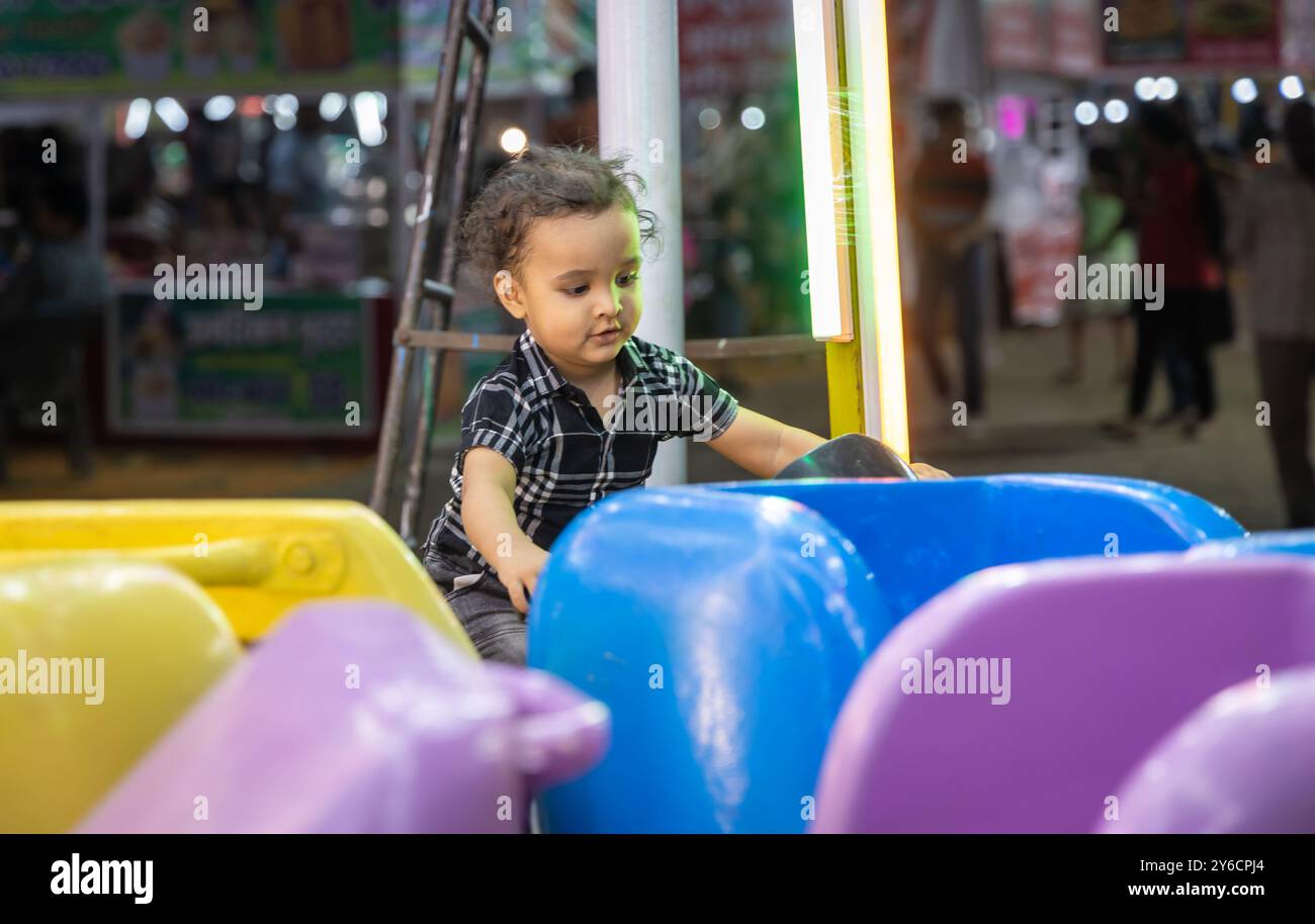 isolated indian kid enjoying baby joy ride at local fair from different ...