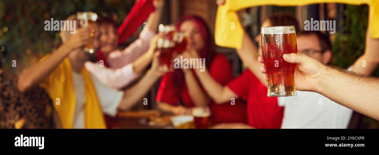 Banner. Fans raise their drinks in unison, toasting victory. Blurred ...