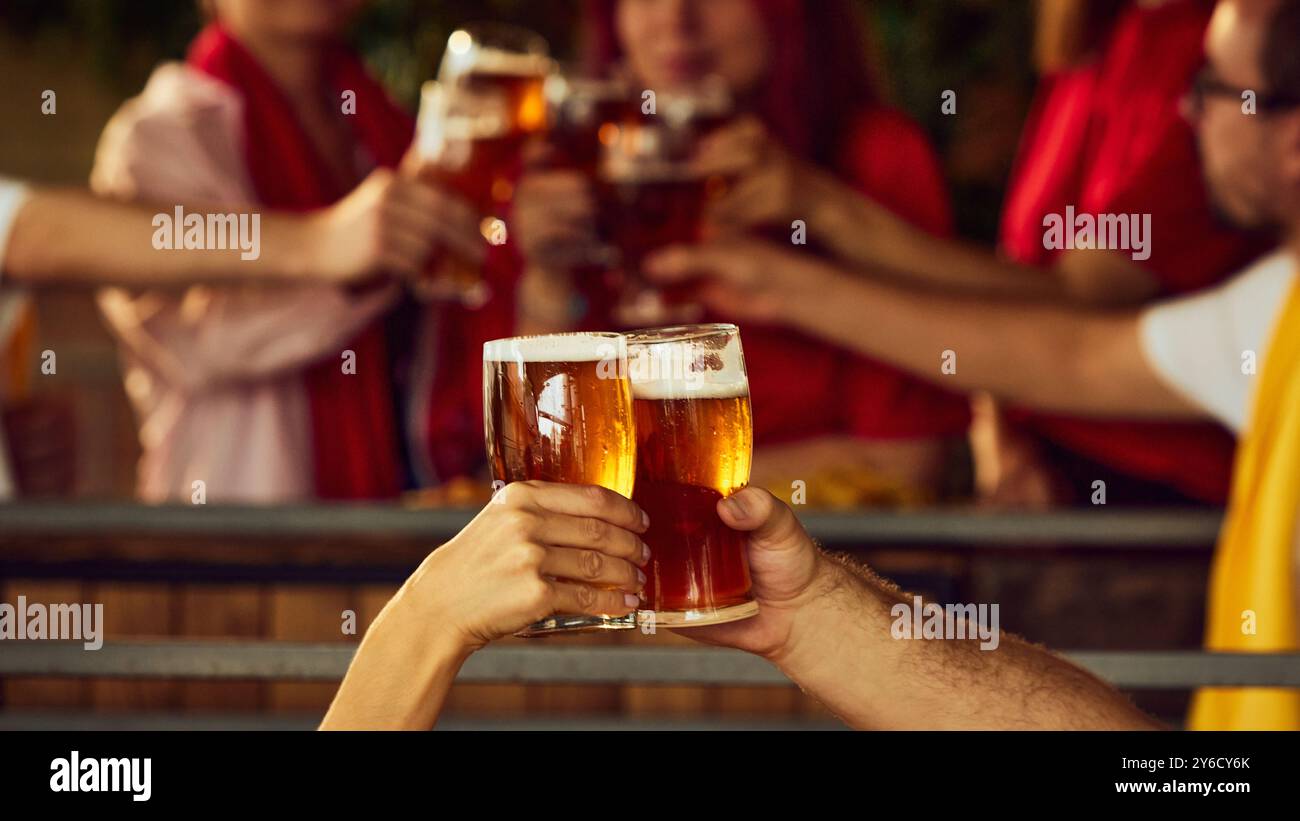 Toast to victory. Fans celebrate with their beers, blurred crowd behind ...