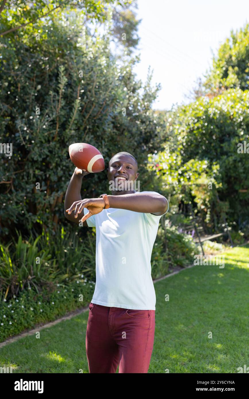 Throwing football, african american man enjoying outdoor activity in ...