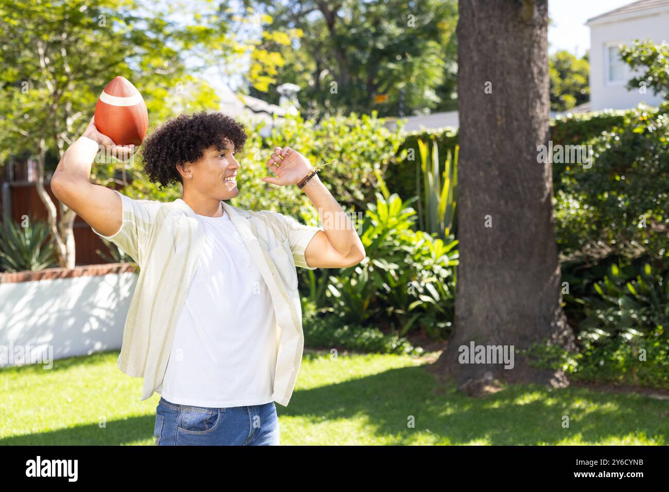 Throwing football, man enjoying outdoor activity in backyard garden ...