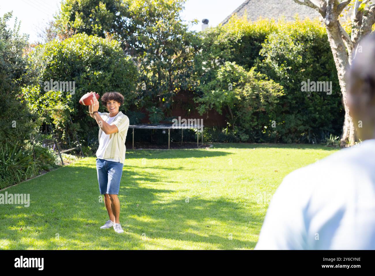 Outdoors, Playing catch, young man throwing football to friend in ...