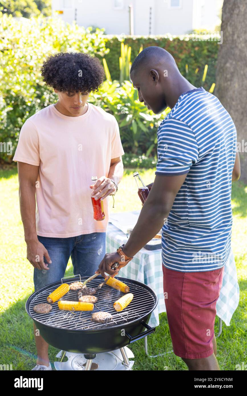 Grilling corn and burgers, two diverse male friends enjoying outdoor ...