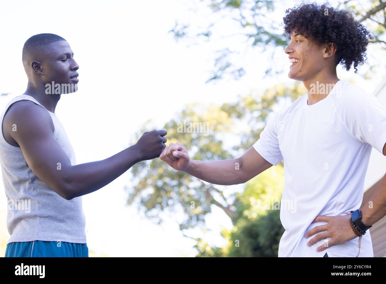 Giving fist bump, two diverse male friends outdoors enjoying time ...
