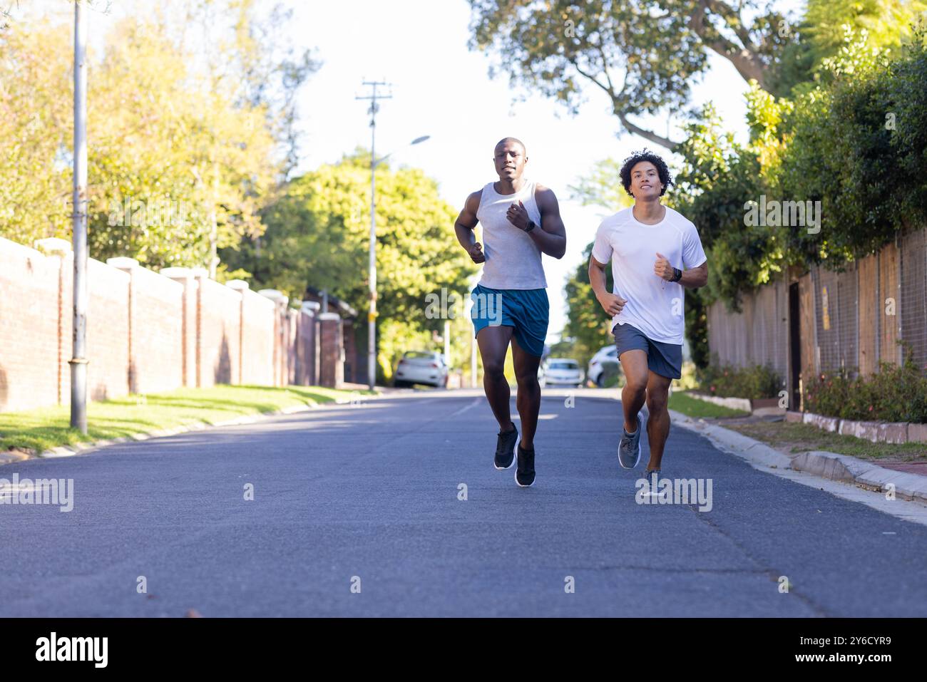Running together on suburban street, two diverse male friends enjoying ...