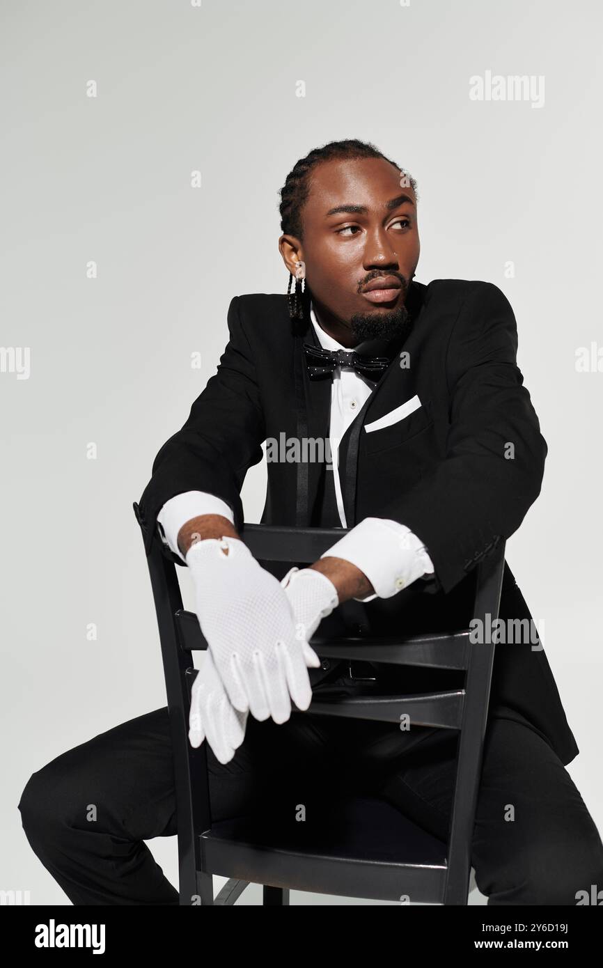 A stylish young man exudes sophistication while poised on a chair ...