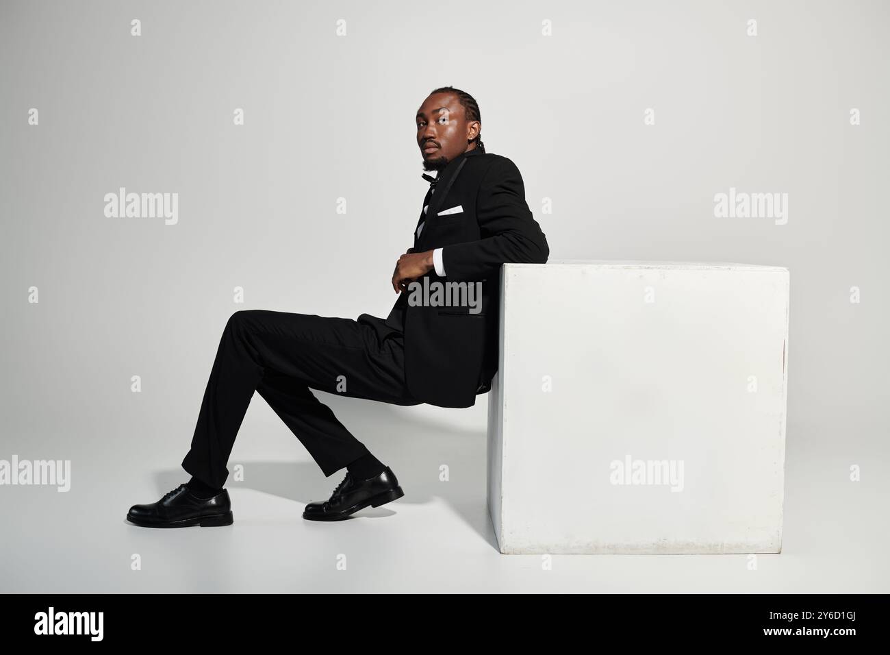 A stylish young man dressed in a sharp suit strikes a poised pose ...