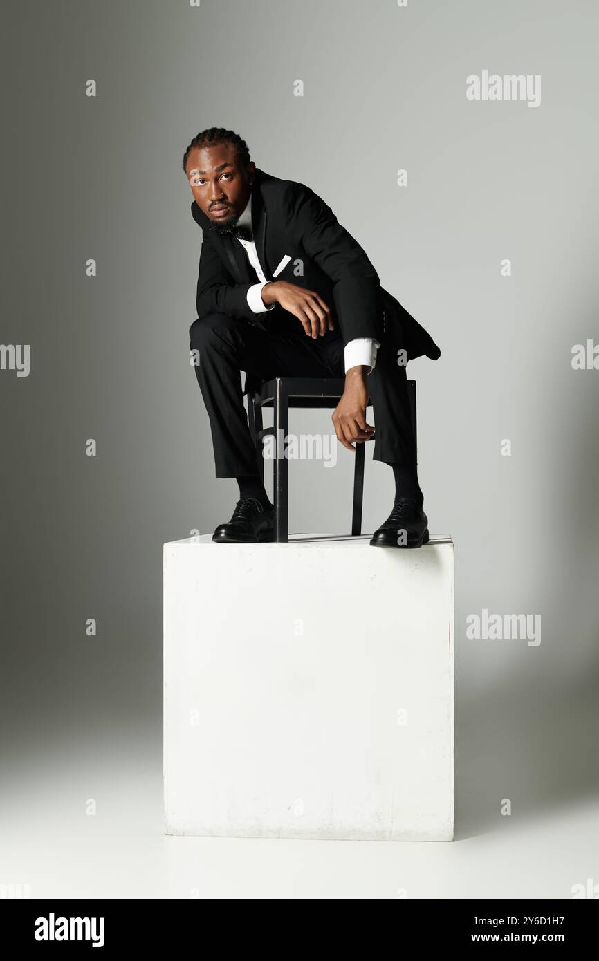 A young man dressed in a sharp suit poses confidently on a pedestal ...