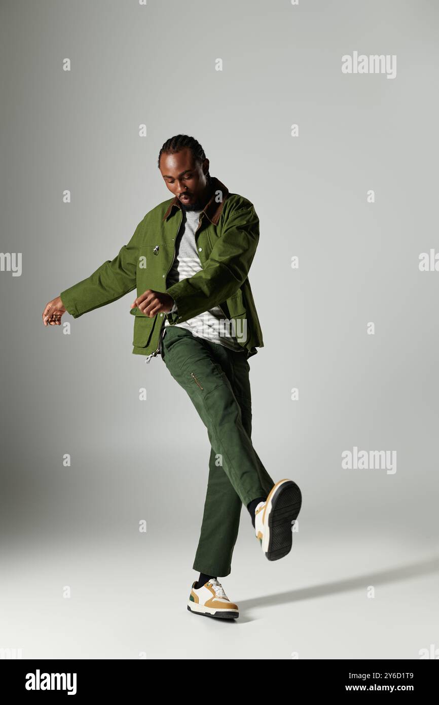 A young man dressed in fashionable green attire strikes a dynamic pose ...