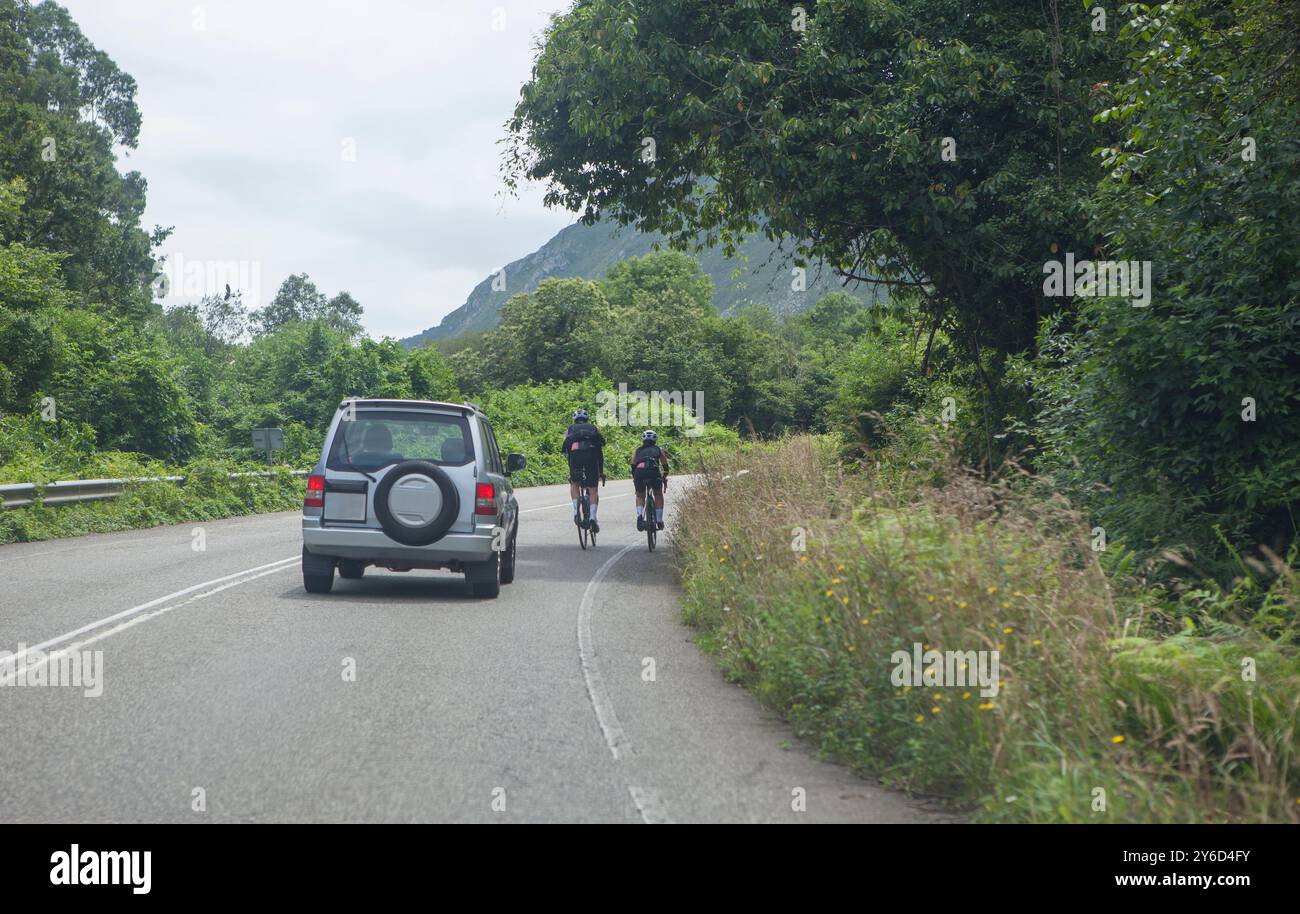 All-terrain vehicle moving slowly behind two cyclists placed side by ...