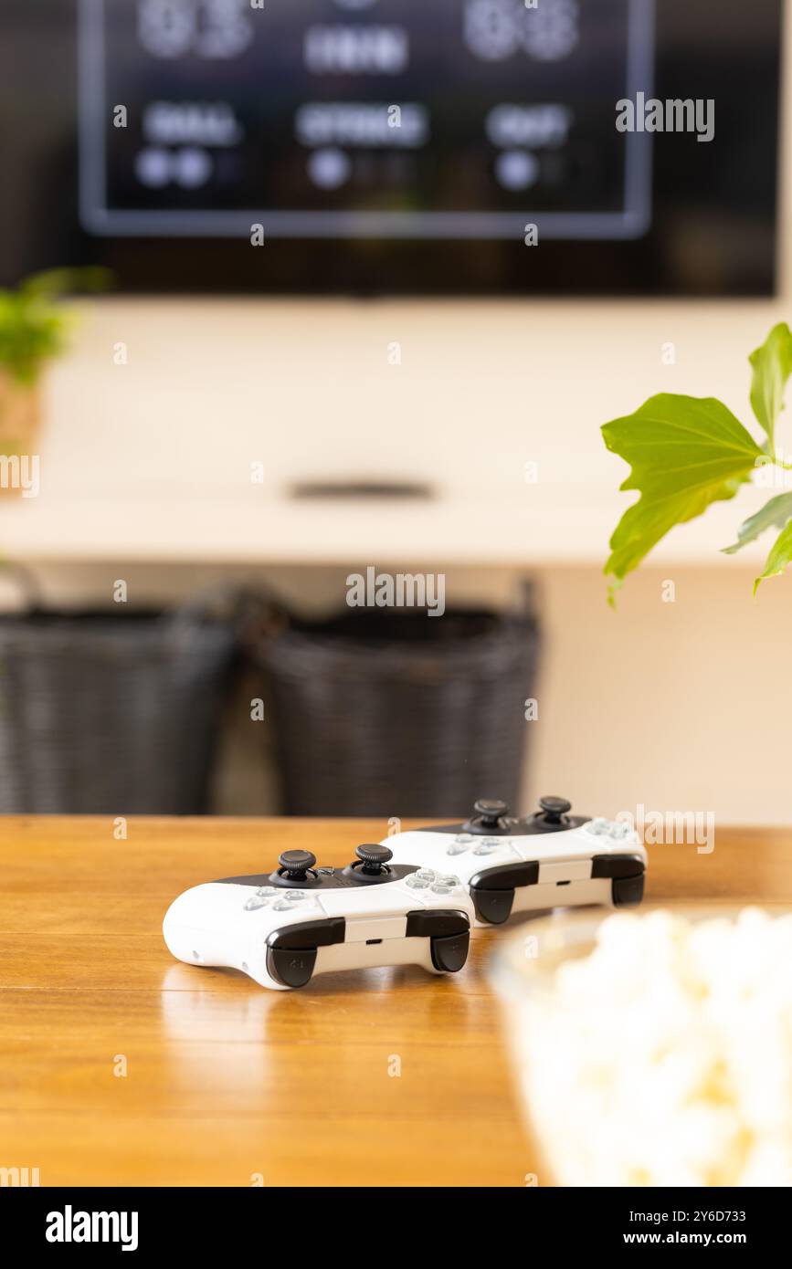 At home, Video game controllers on table with TV screen in background ...