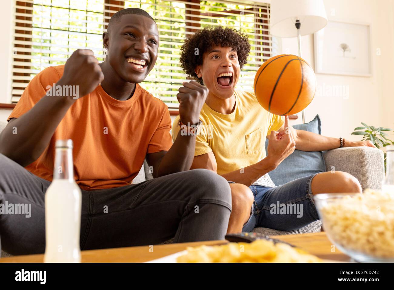 At home, Cheering excitedly, two diverse male friends watching ...