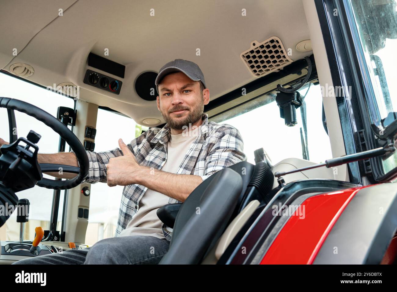 Male farmer sitting in a farm tractor, giving a thumbs-up. Man sitting ...