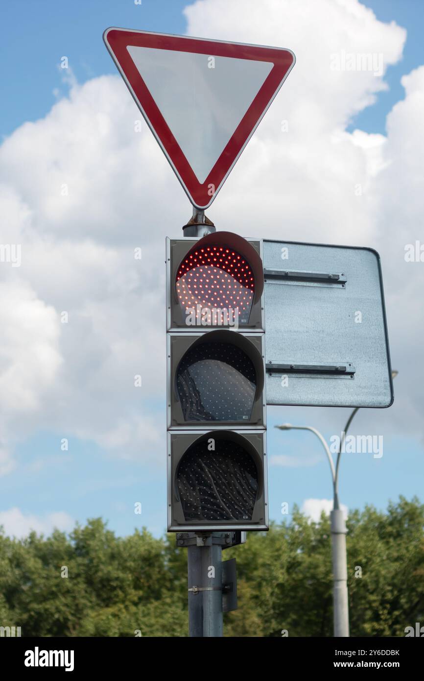 A bright red traffic light is hanging down from a tall pole, clearly ...