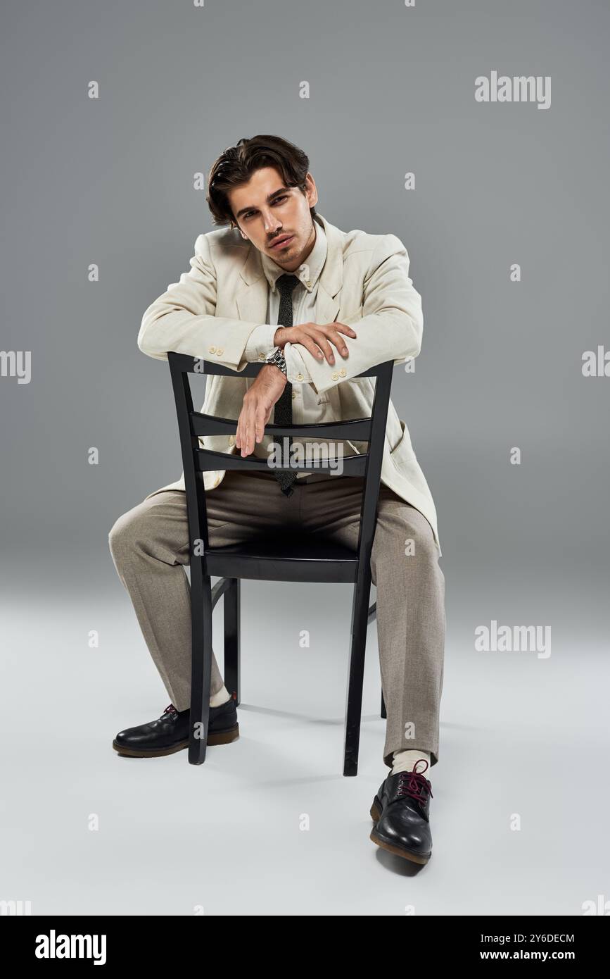 A young man showcases his charm in elegant formal wear while seated on ...