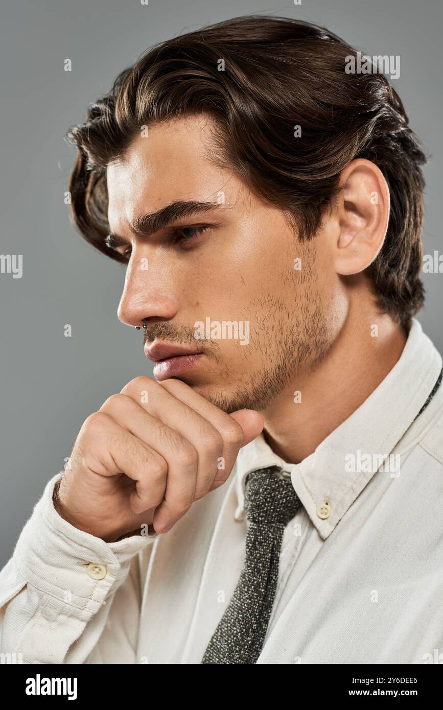 A handsome young man dressed in sharp formal attire contemplates in a ...