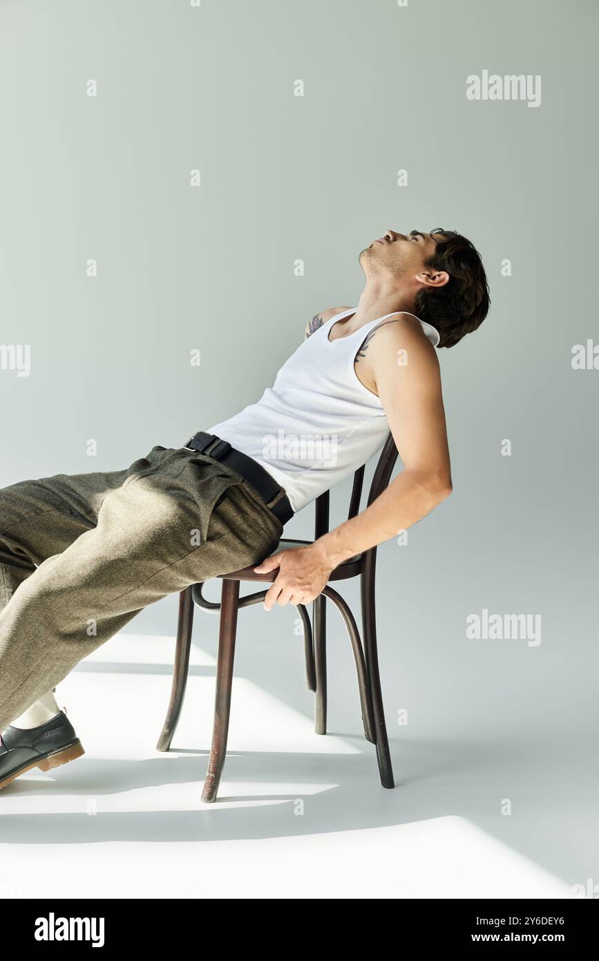 A stylish young man displays a relaxed pose while leaning back on a ...