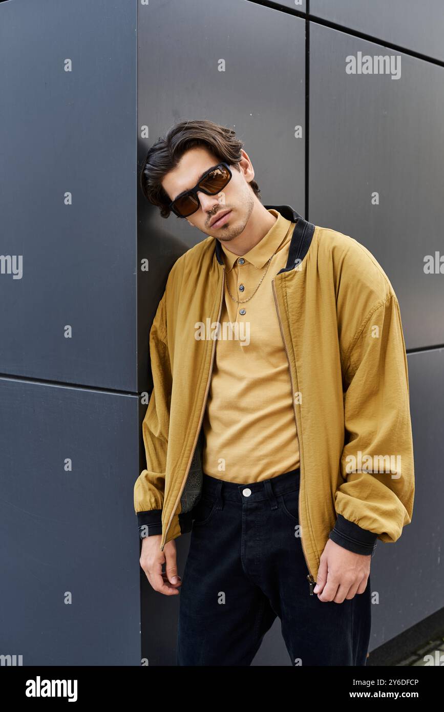 A young man in a fashionable autumn outfit confidently poses near sleek ...
