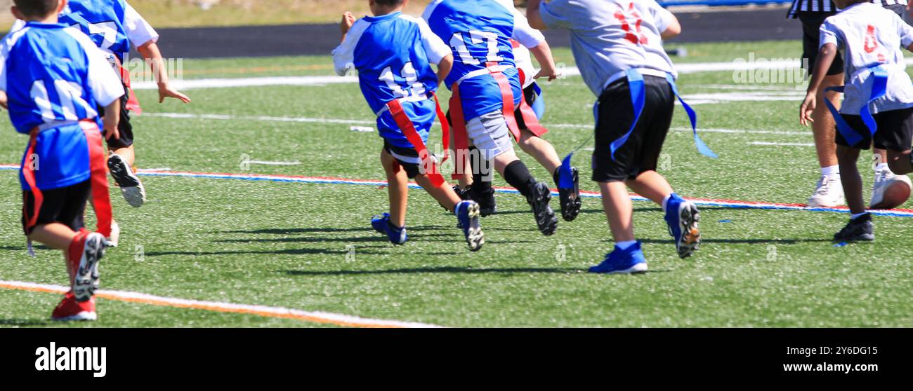 Young boys chasing each other playing youth flag football on a turf ...