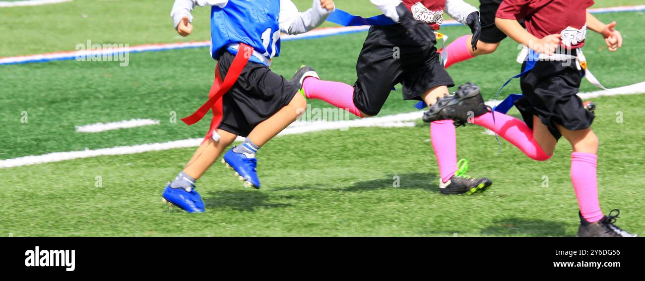 Young boys running on a football field wearing flags during a youth ...