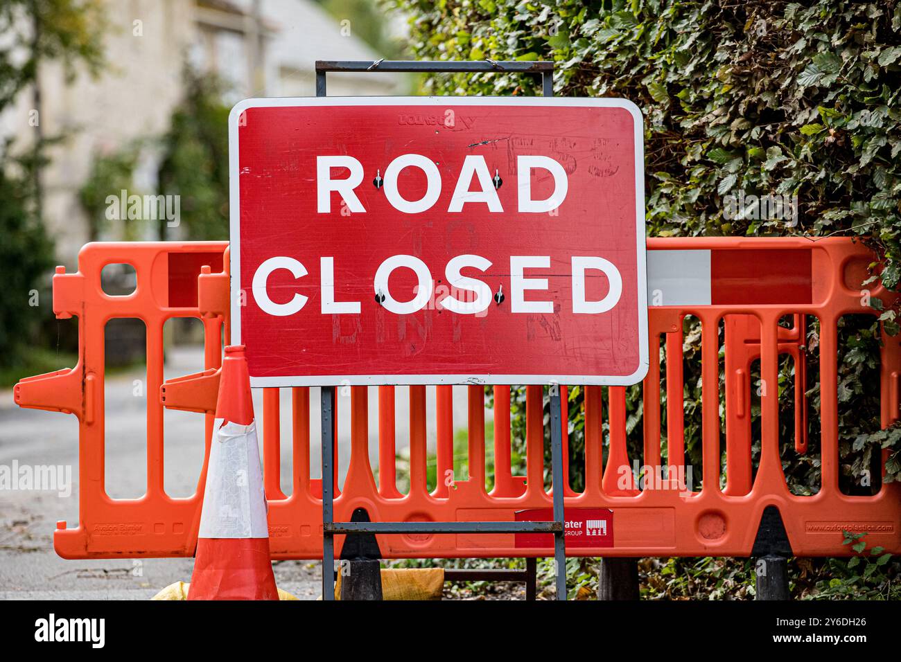 Red Road Closed Ahead sign with white lettering, with an orange plastic ...