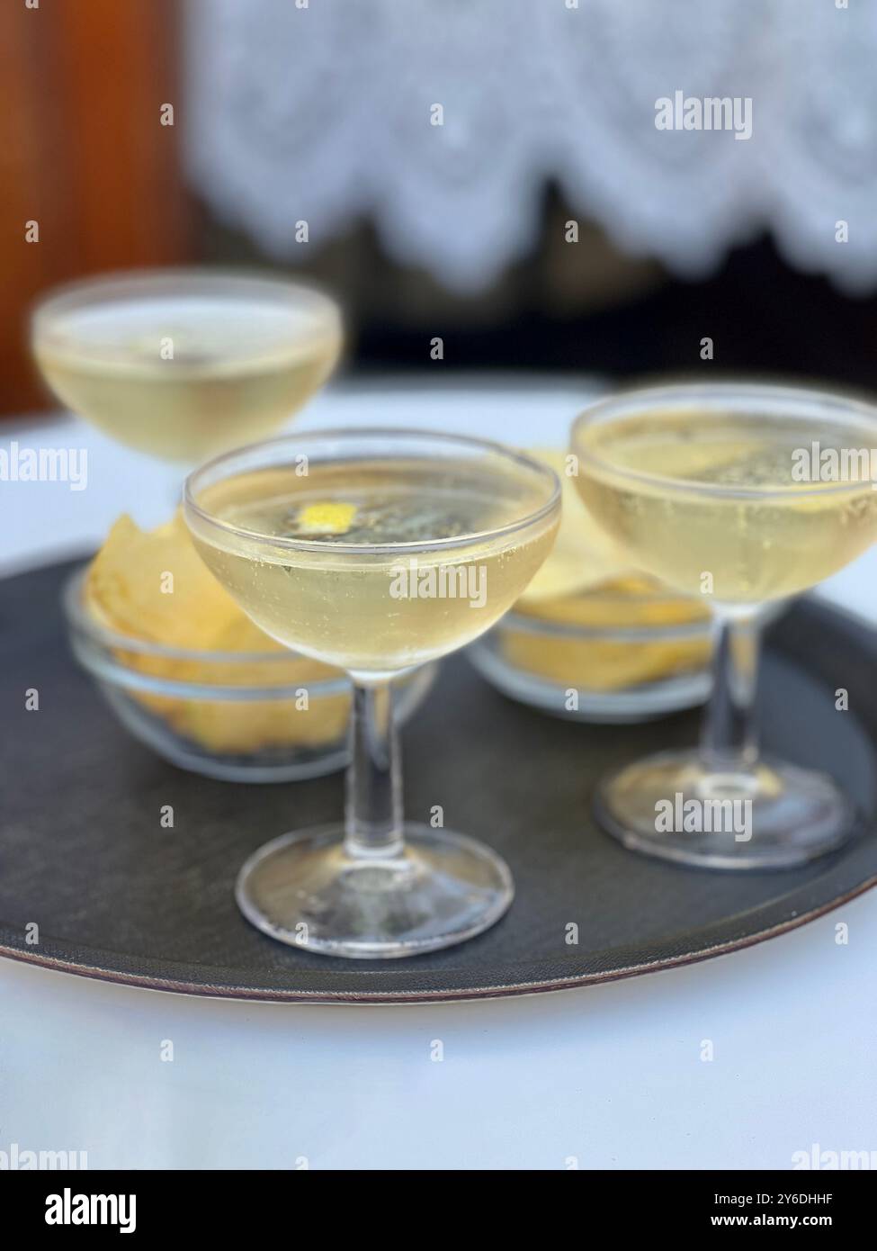 Three cocktails on a bar tray with potato chips or crips. Taken at an ...